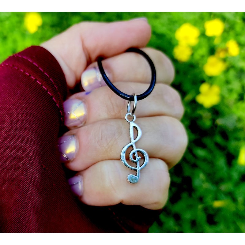 Divertido colgante de metal en forma de CLAVE de SOL.Incluye cordón y caja.